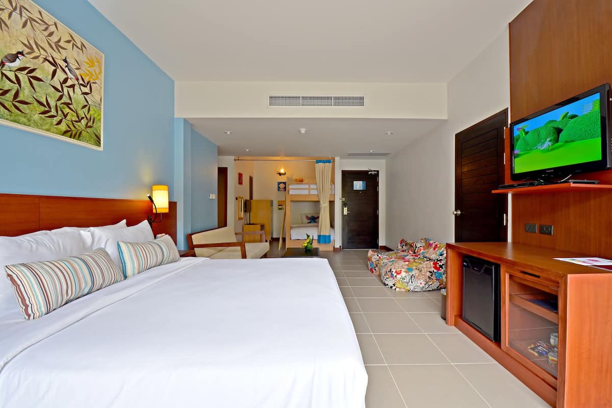 Quarto de hotel com uma cama grande, televisão, escrivaninha e guarda-roupa.
