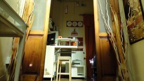 Um corredor com uma porta de madeira que dá para um quarto com uma mesa e uma cadeira.