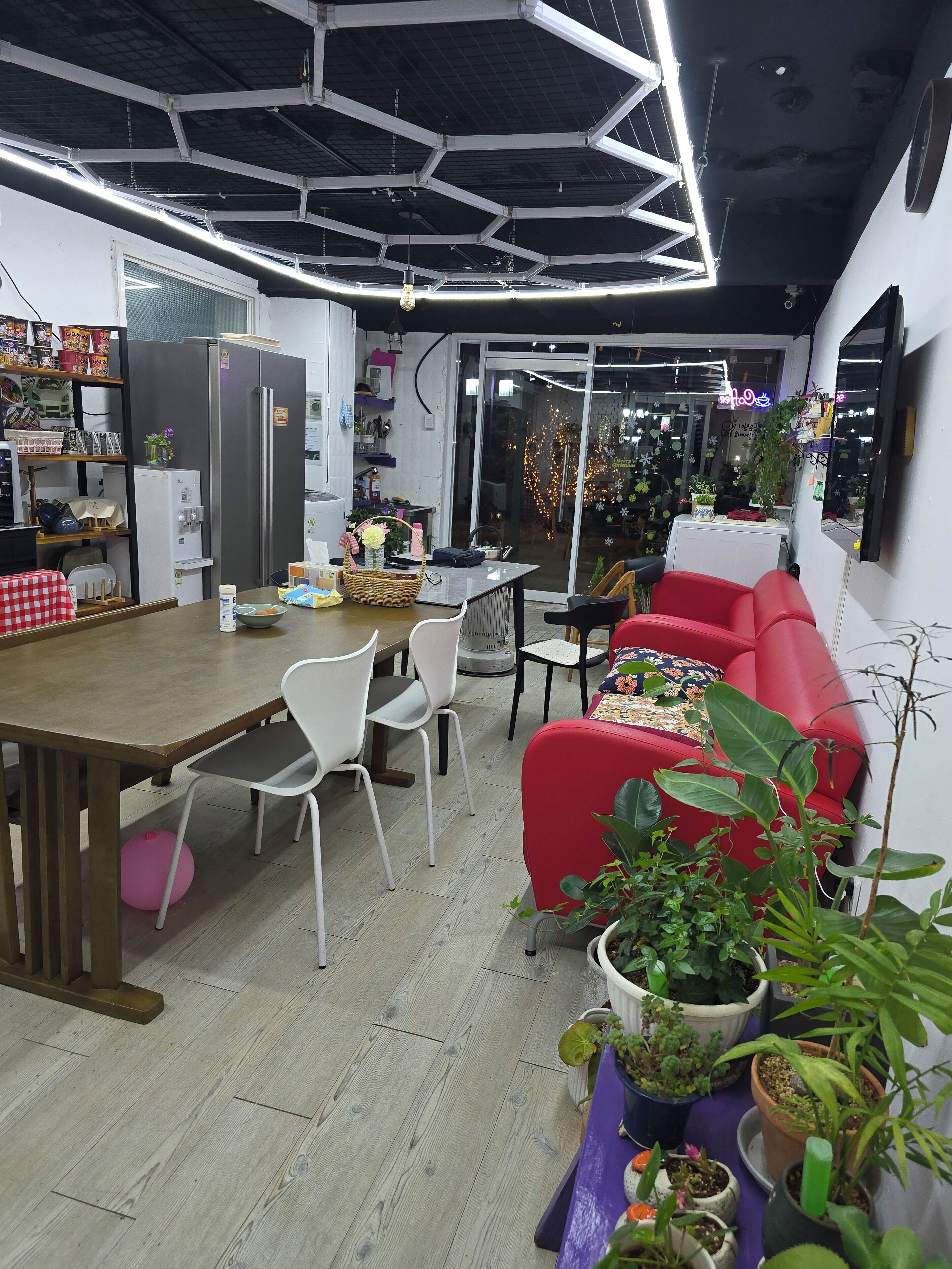 Um interior moderno com área de jantar, um sofá vermelho e diversos vasos com plantas.