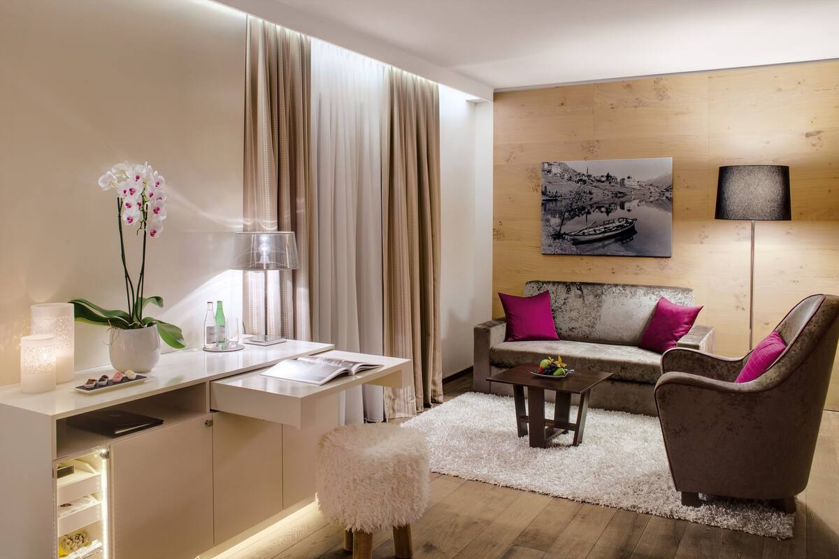 Quarto de hotel moderno com escrivaninha, sofá e um quadro na parede.