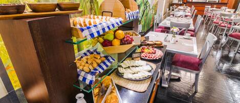 Uma área de buffet com diversos tipos de comida e uma sala de jantar com mesas e cadeiras.