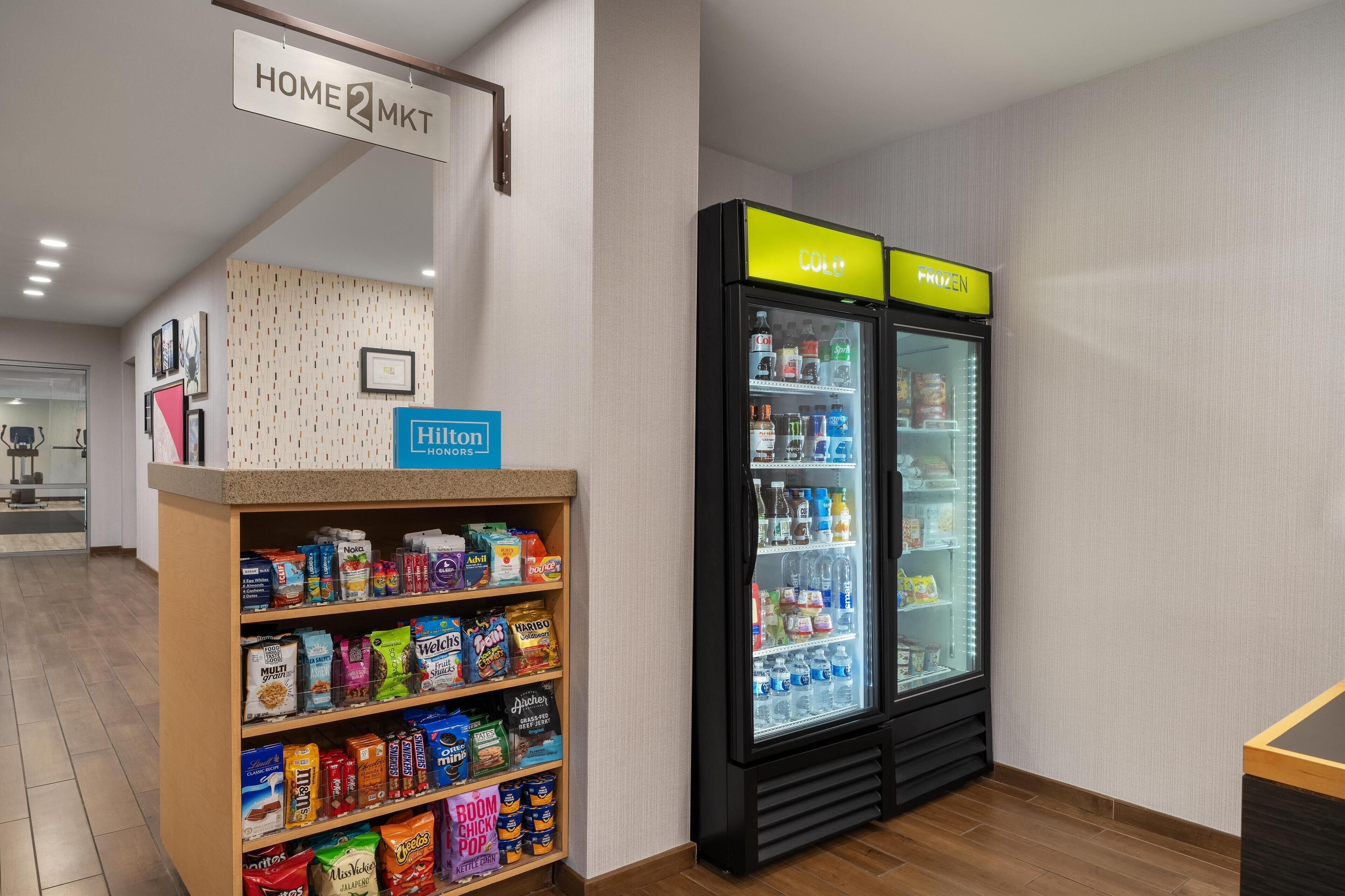 Um saguão de hotel com uma máquina de venda de lanches e uma placa para Hilton Home2MKT.