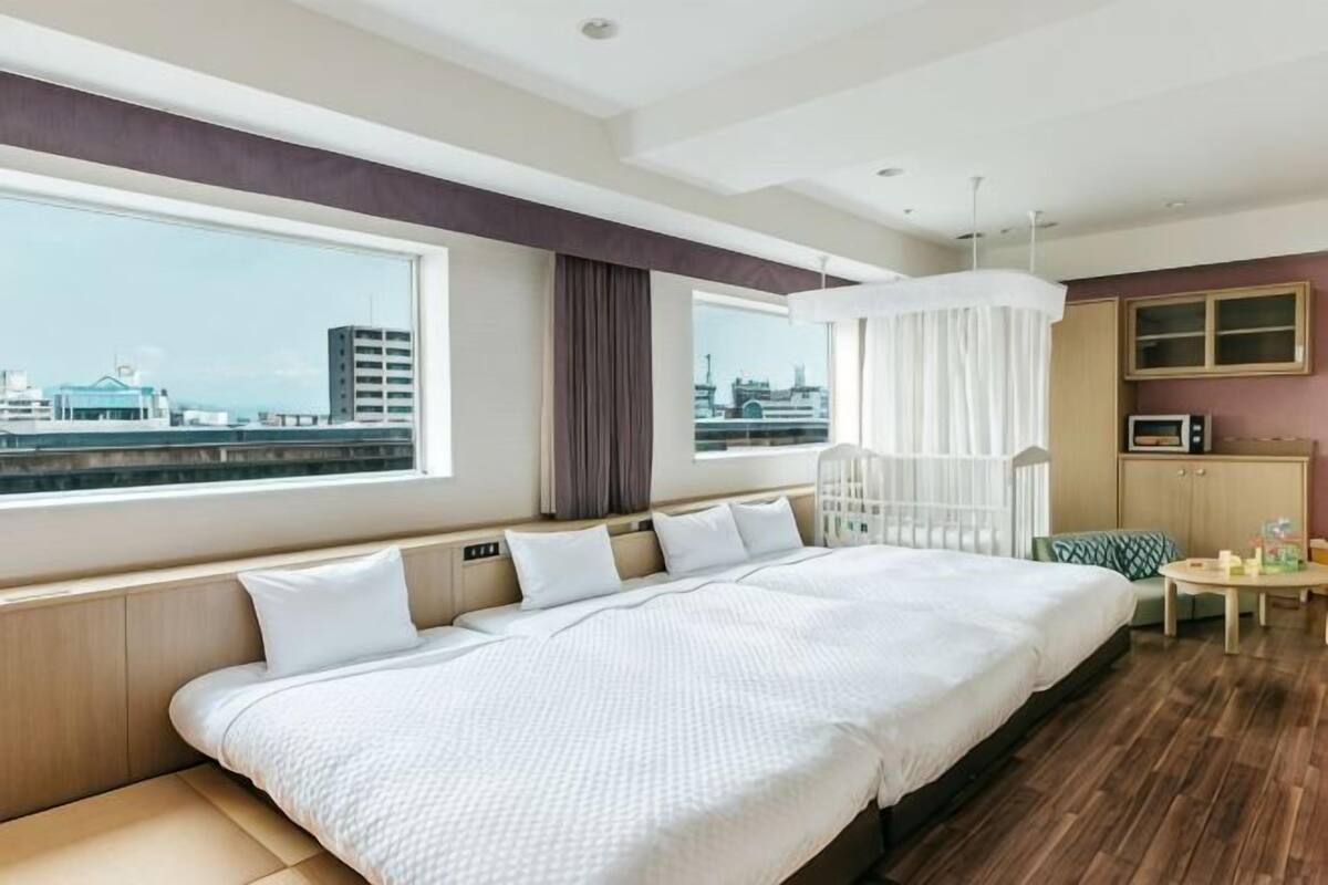 Quarto de hotel com uma cama grande, vista da cidade, área de refeições e micro-ondas.