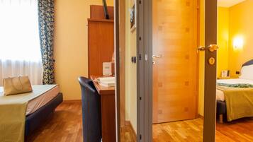 Quarto de hotel com cama, escrivaninha e guarda-roupa.