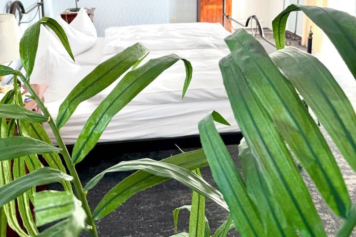 Quarto de hotel com cama, cômoda, espelho e janela com cortinas.
