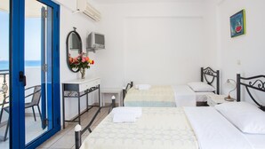 Quarto de hotel com duas camas, uma escrivaninha, uma cadeira, televisão e varanda com vista para o mar.