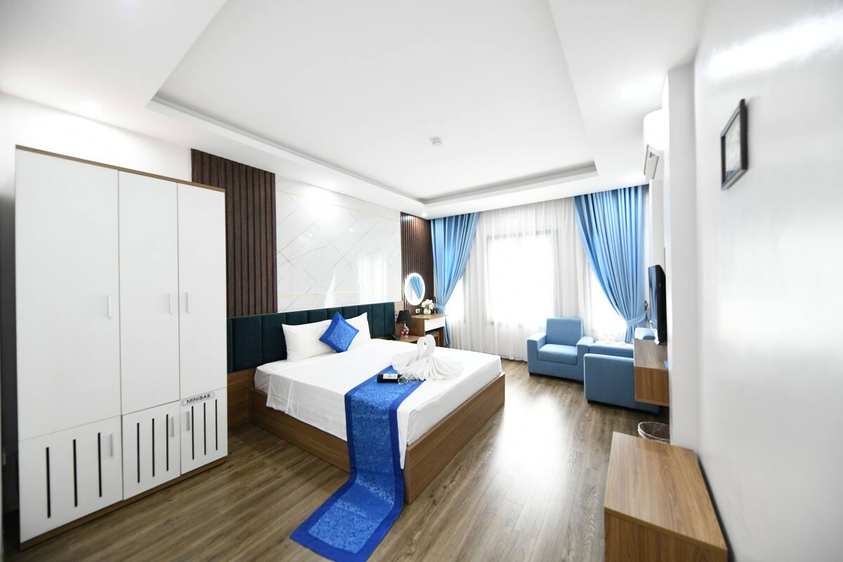 Quarto de hotel moderno com cama grande, guarda-roupa, área de estar e televisão.