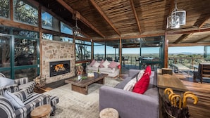 Uma sala de estar ampla com lareira de pedra, assentos confortáveis e grandes janelas com vista panorâmica.