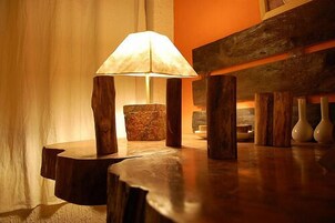 Uma mesa de madeira com uma luminária, uma escultura de pedra e vasos.