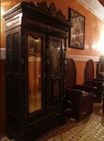 Quarto com um armário grande e elaborado em madeira, com portas de vidro, um tapete estampado e um quadro na parede.