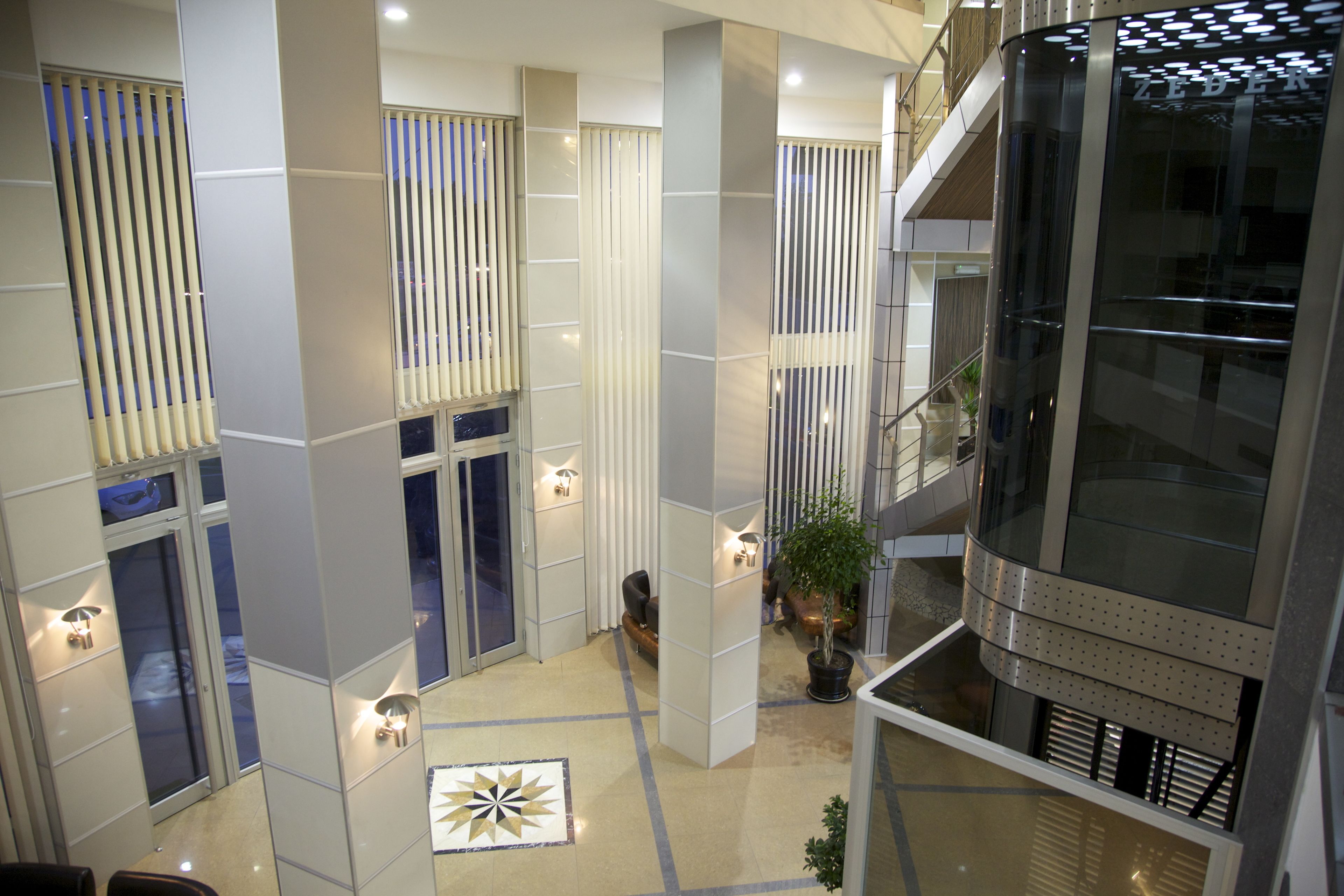Um hall de hotel moderno com um átrio central, vários andares e uma escadaria.