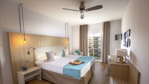 Quarto de hotel moderno com uma cama grande, mesas de cabeceira, uma escrivaninha e um ventilador de teto.