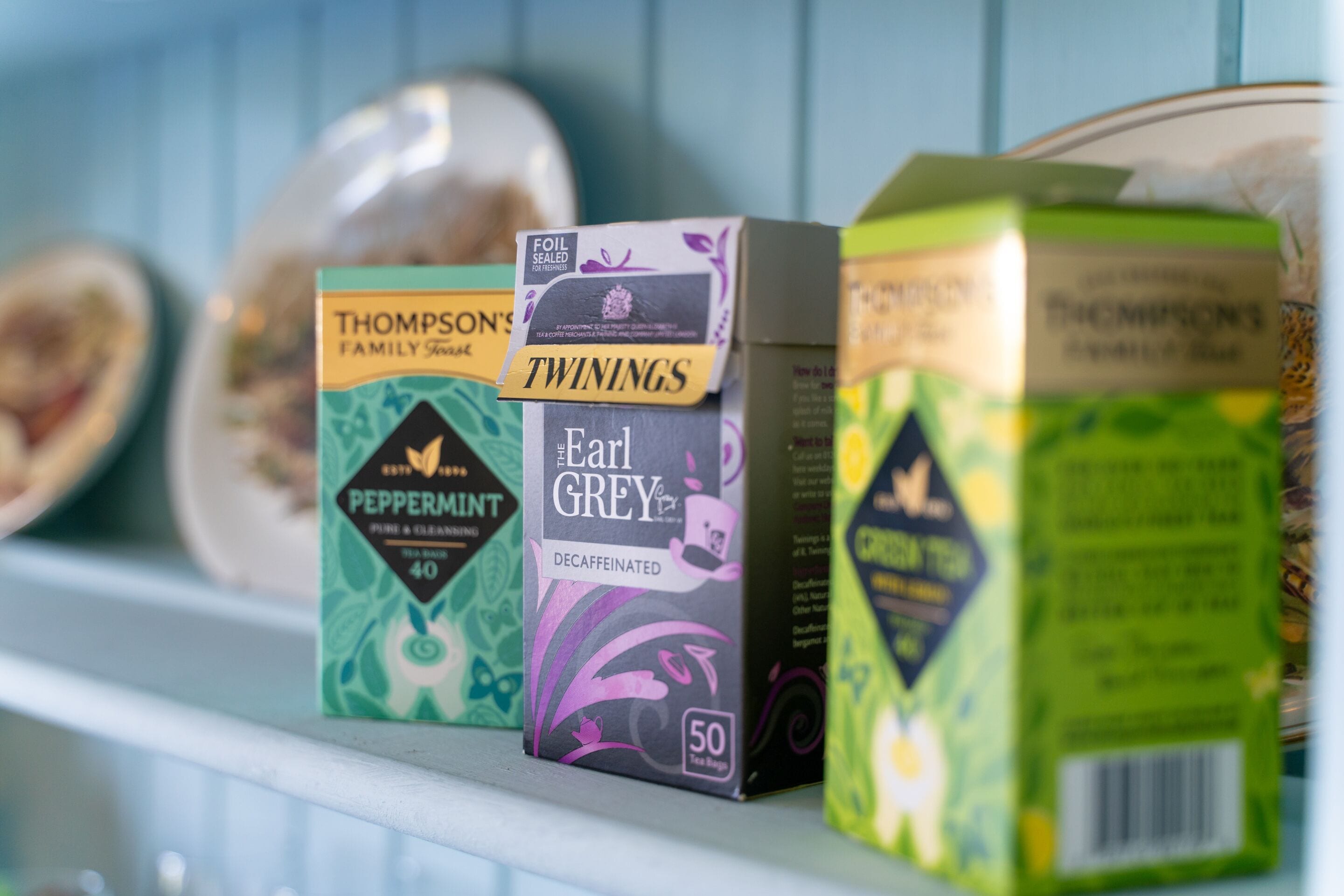 Uma prateleira com caixas de chá, incluindo marcas como Thompson's e Earl Grey.