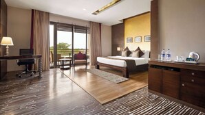 Quarto de hotel com cama, escrivaninha, cadeira e vista para o exterior.