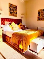 Quarto de hotel com cama grande, mesa de cabeceira e duas luminárias fixadas na parede.