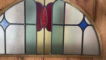 Uma janela de vitrais com topo semicircular e grade de painéis coloridos.