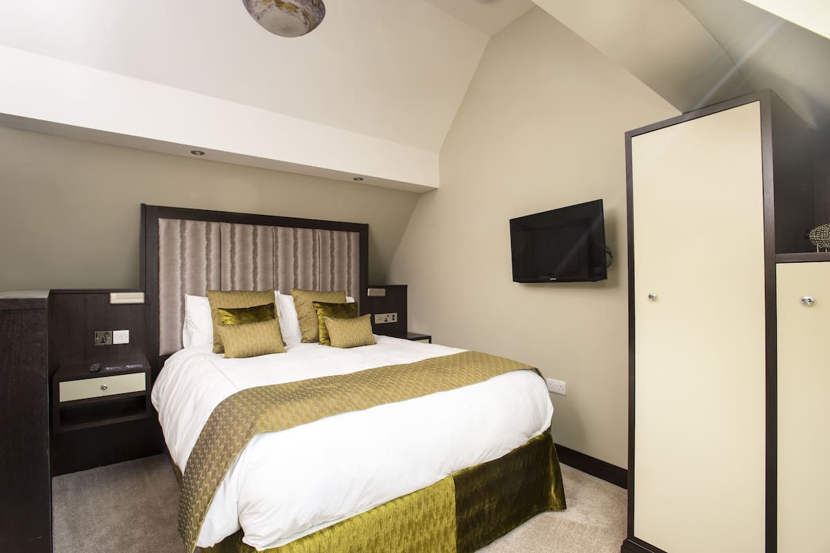 Quarto de hotel com uma cama grande, televisão na parede e um guarda-roupa.