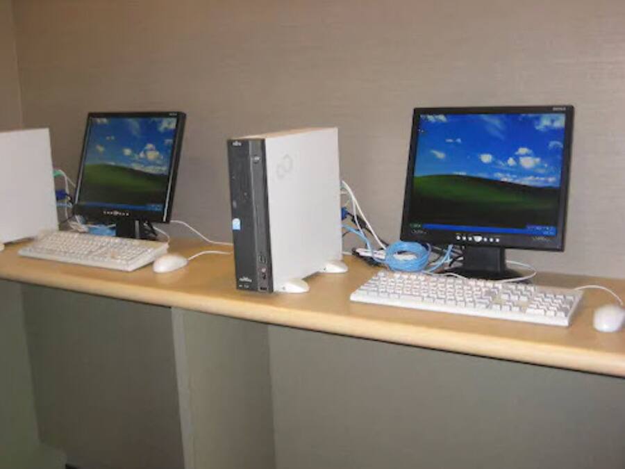 Dois computadores de mesa sobre uma escrivaninha, com teclados e ratos.