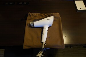 Um secador de cabelo Panasonic sobre um pano castanho num tampo de madeira.