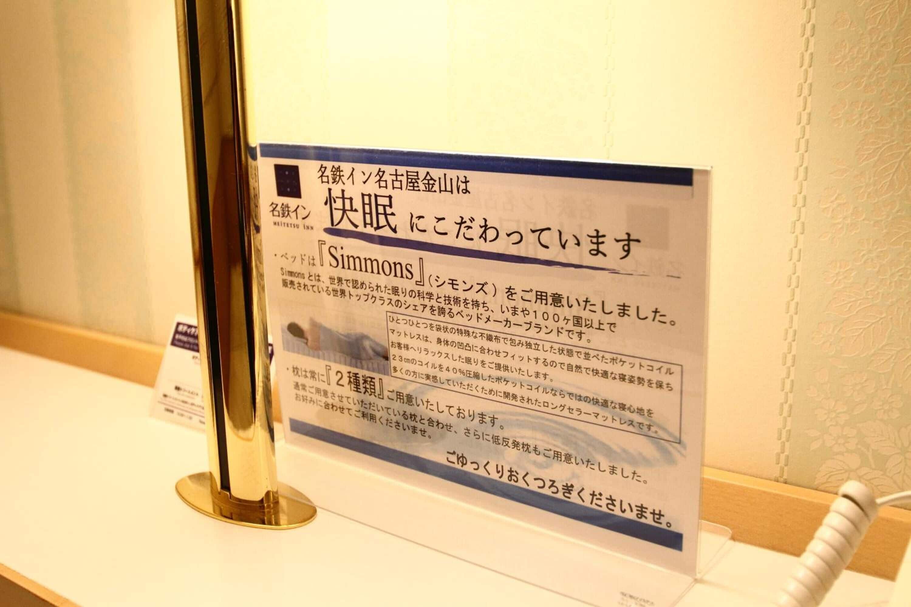 Uma placa com texto em japonês, um objeto metálico e um cordão branco.