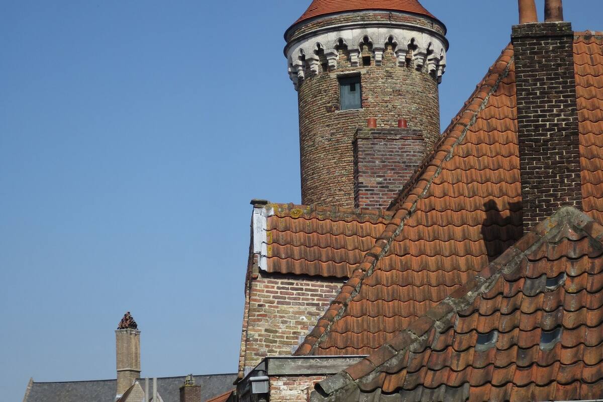 Um edifício histórico com uma torre e telhado cônico, com detalhes em tijolo.