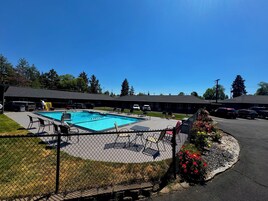 Uma área de piscina com espreguiçadeiras e um deck cercado.