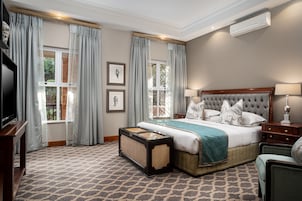 Quarto com cama grande, televisão e janela com cortinas.