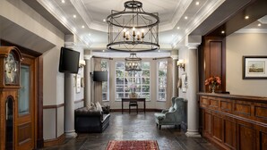 Uma sala de estar espaçosa com um grande candelabro, lareira e televisão na parede.