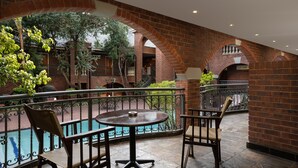 Uma área de pátio com mesa redonda e cadeiras, piscina e paredes de tijolos.