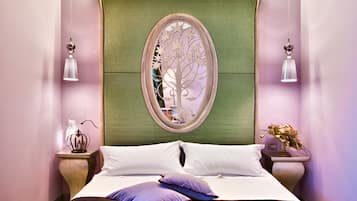 Uma cama bem arrumada com travesseiros brancos e roxos, cabeceira verde e um espelho decorativo.