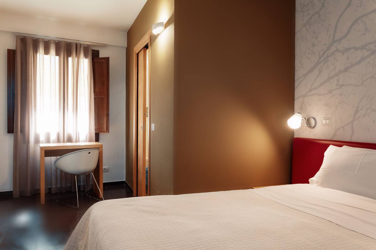 Quarto de hotel com uma cama, uma mesa e uma cadeira.