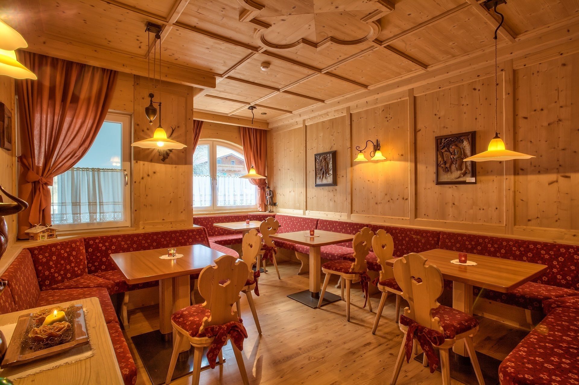 Restaurante acolhedor com paredes e teto de madeira, com cabines e mesas estofadas com flores.