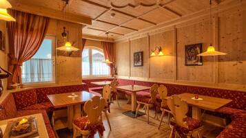 Restaurante acolhedor com paredes e teto de madeira, com cabines e mesas estofadas com flores.