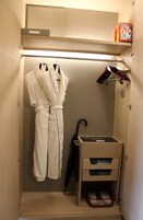 Um closet amplo com um roupão pendurado, um cabideiro, um sapateiro e um cesto para sapatos.