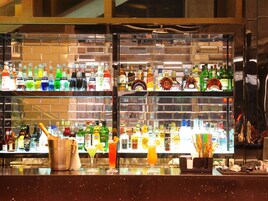 Uma área de bar com prateleiras repletas de garrafas de bebidas, um balde e alguns coquetéis.