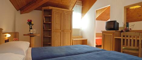 Quarto com duas camas, móveis de madeira, televisão e janela.