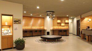 Um hall moderno com área de estar central, detalhes em madeira e iluminação embutida.