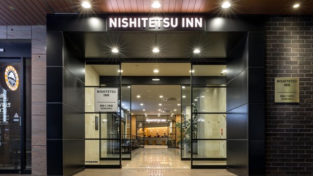 Exterior do NISHITETSU INN com design moderno, apresentando portas de vidro e uma placa de identificação acima da entrada.