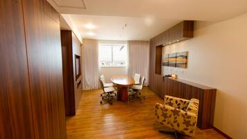 Uma sala de conferências com piso de madeira, uma mesa redonda e quatro cadeiras.