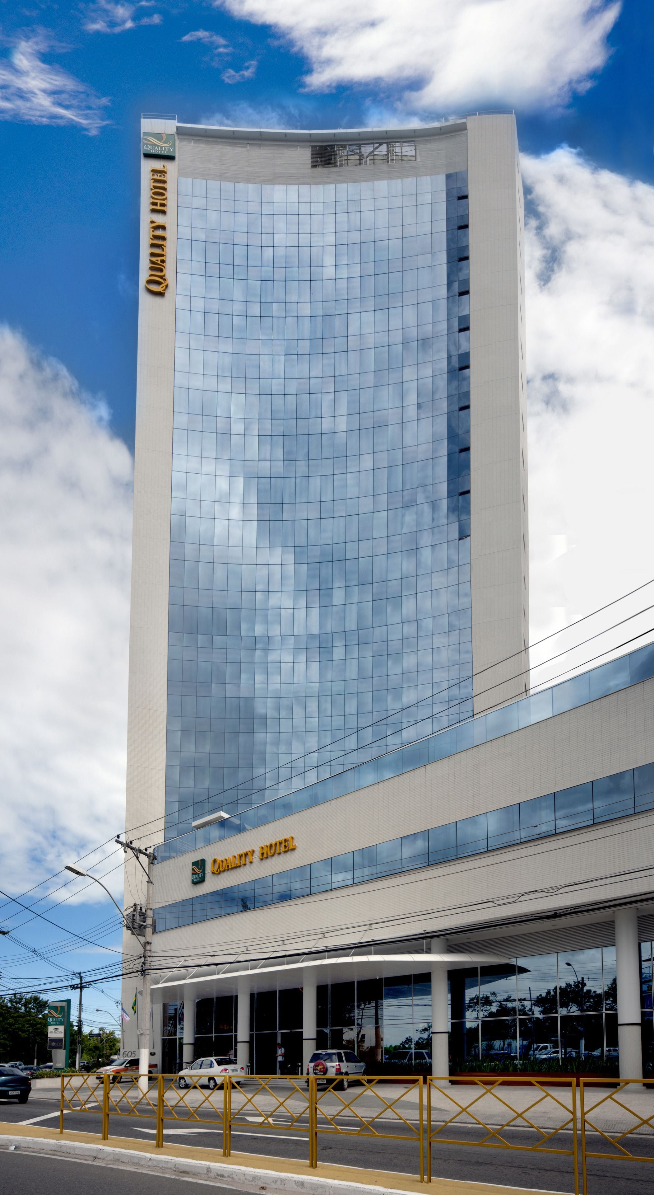 Um hotel alto com fachada de vidro refletivo e um letreiro chamativo com a inscrição 