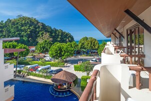 Um resort com piscina, um gazebo e vista para o mar e colinas arborizadas.