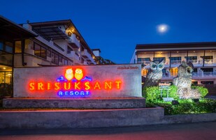 Placa do Srisuksant Resort com luzes de neon iluminadas, uma lua no céu e uma estátua decorativa de coruja.
