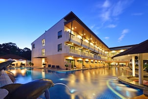 Hotel moderno com piscina, várias varandas e fachada bem iluminada.