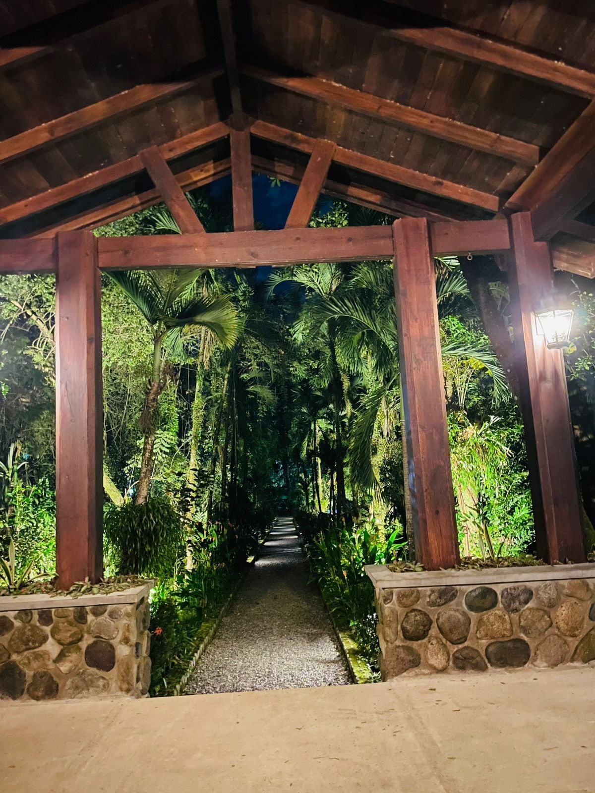 Um caminho coberto ladeado por vegetação exuberante e muros de pedra.