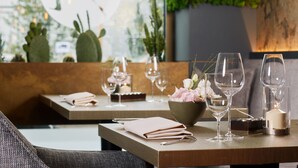 Uma mesa de jantar posta com taças de vinho, uma vela e um arranjo de flores.