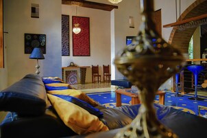 Um quarto com sofá, lustre e tapete azul estampado.