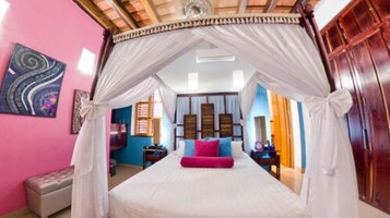 Quarto com cama de dossel, parede rosa e parede azul de destaque.