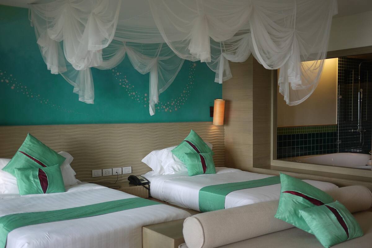 Quarto de hotel com duas camas, um espelho grande, mesa de cabeceira e telefone fixado na parede.