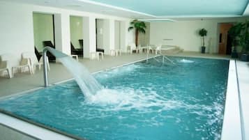 Piscina com um elemento aquático, rodeada por espreguiçadeiras e uma escadaria.