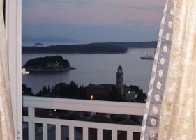 Vista da janela sobre um corpo de água, com uma ilha distante e uma torre.